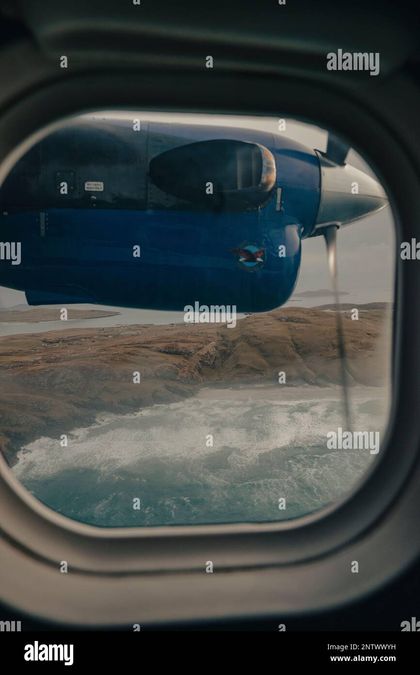 Sea cliffs seen through the window of a Twin Otter aircraft on approach ...
