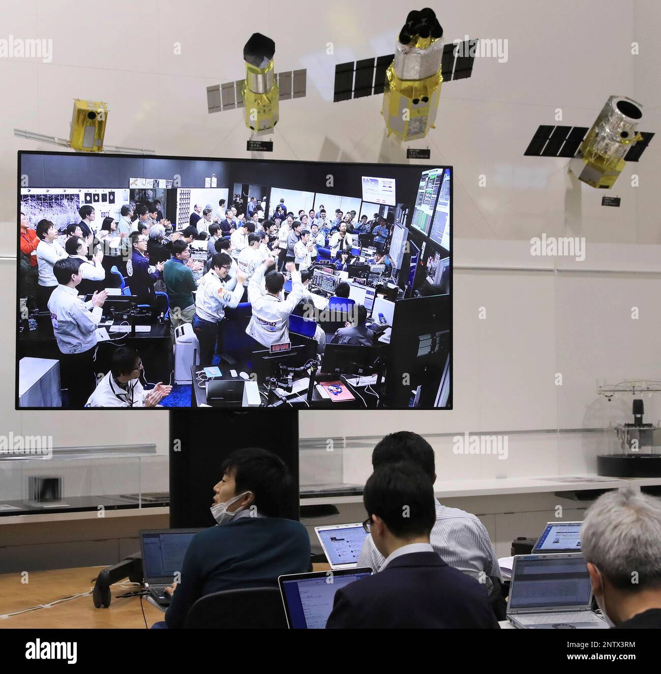 A monitor shows people shout for joy at the control room at the press ...