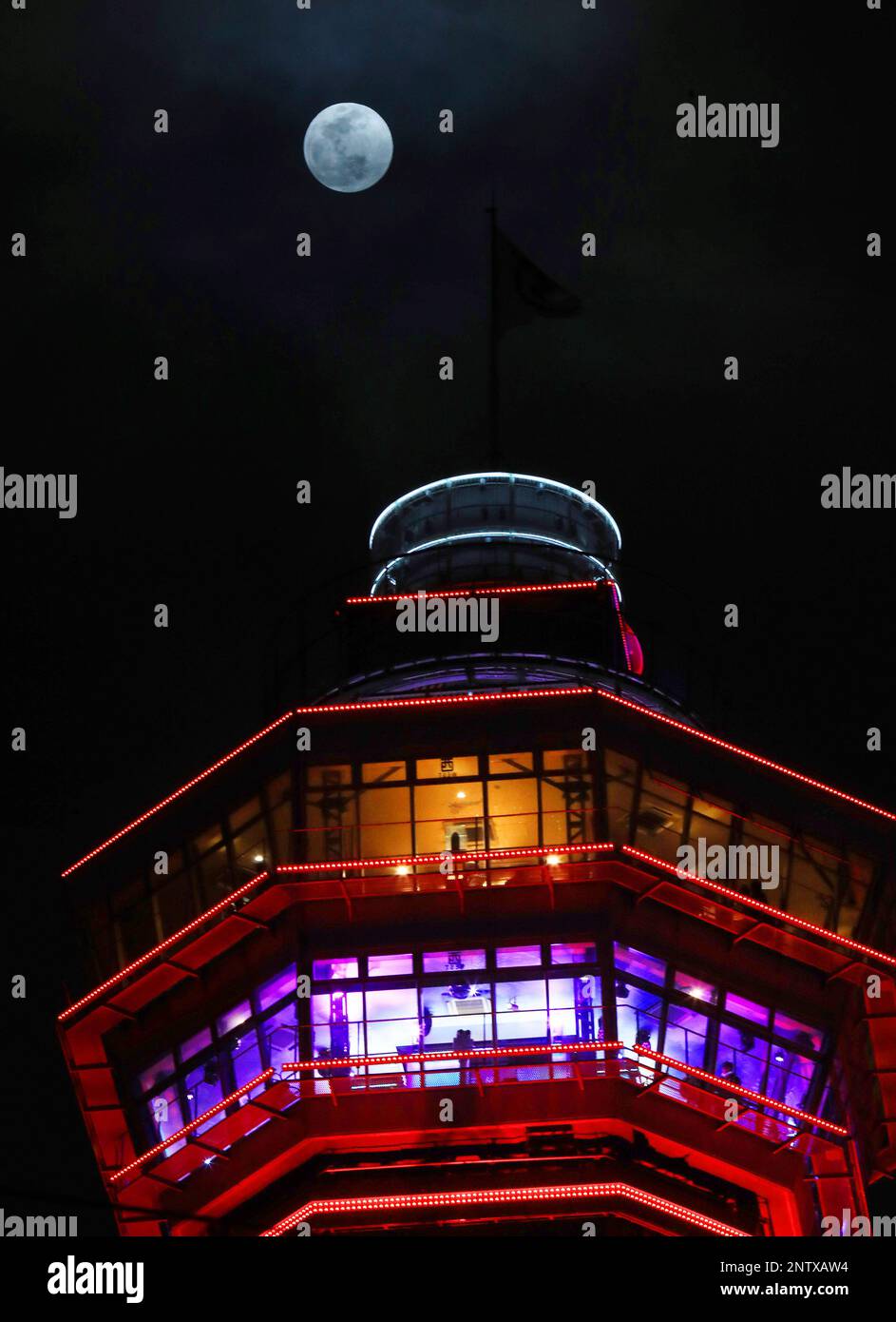 The full moon is seen avobe Tsūtenkaku in Osaka City, Osaka Prefecture ...