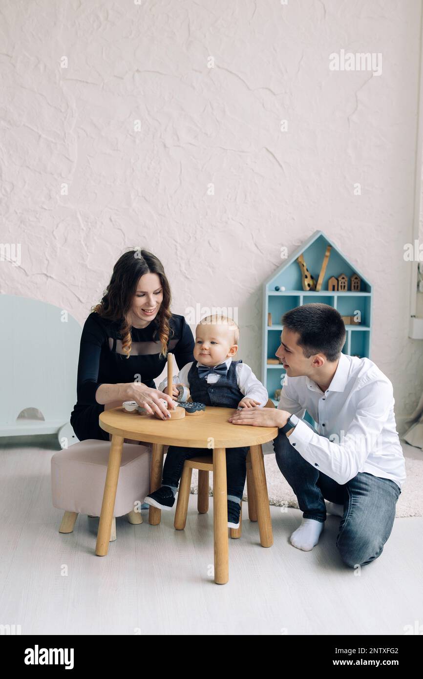 Young parents play with their toddler boy and build together pyramid ...
