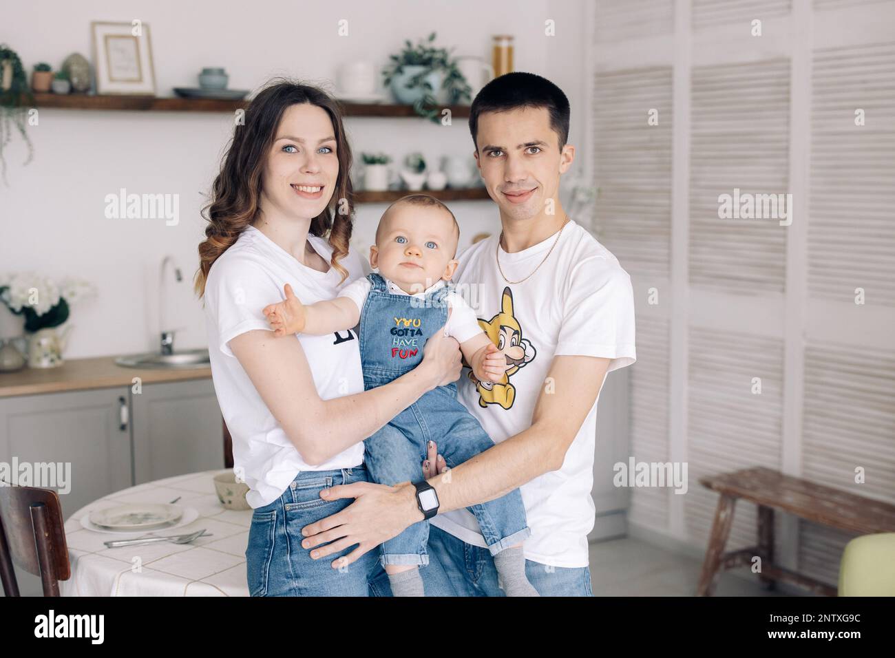 Young happy parents stand and pose with their toddler boy against ...