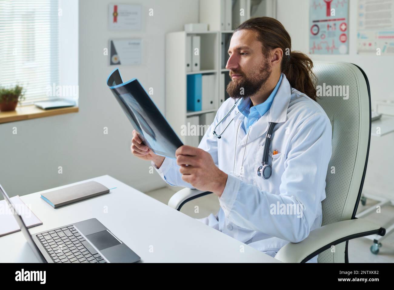 Confident male radiologist looking at x-ray result while sitting in ...