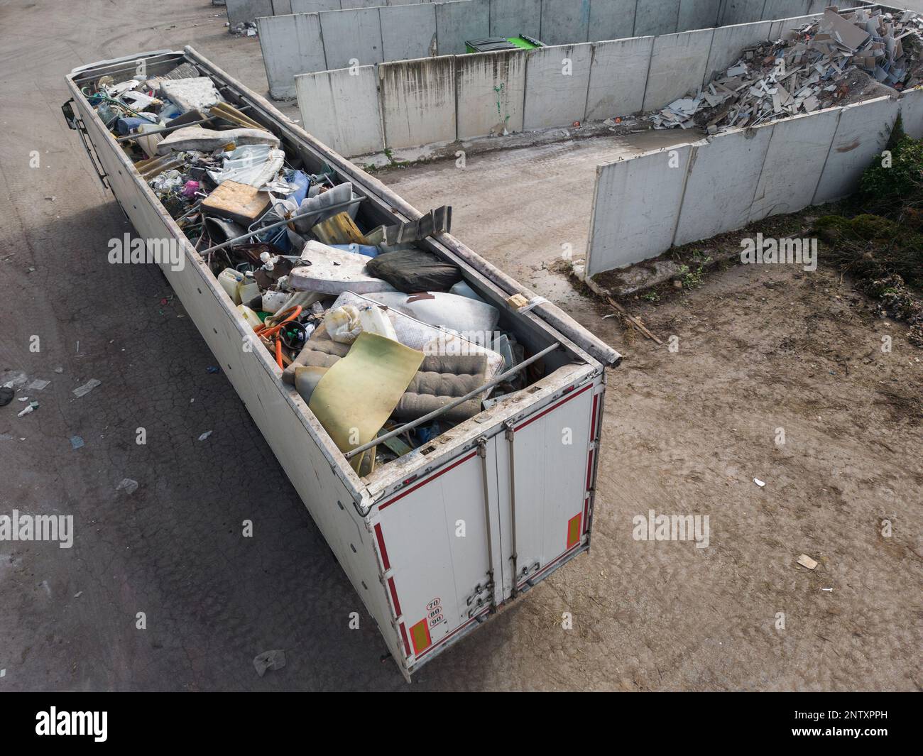 Recycling center truck full of household waste, parked near box areas ...