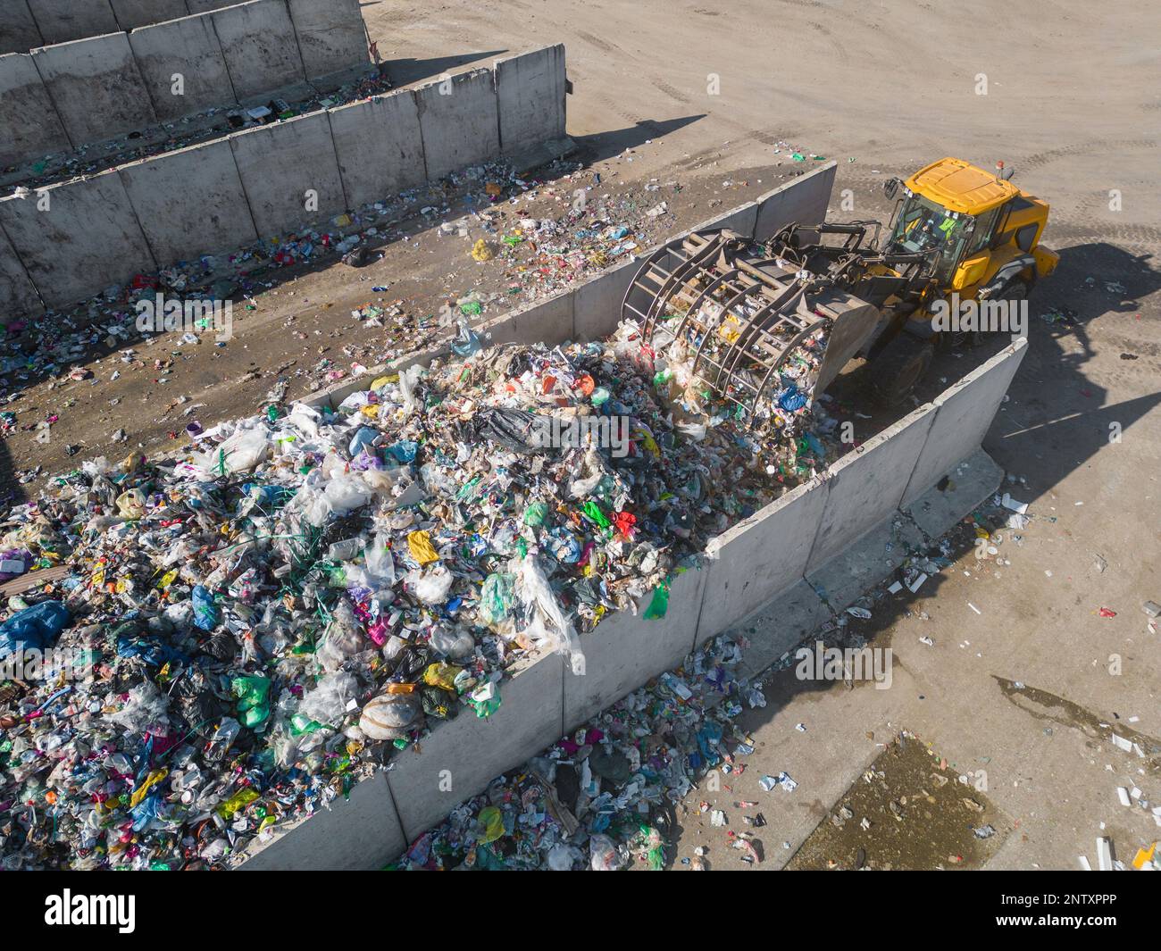 Yellow wheel loader, with lifted scrap grapple, moving along the ...