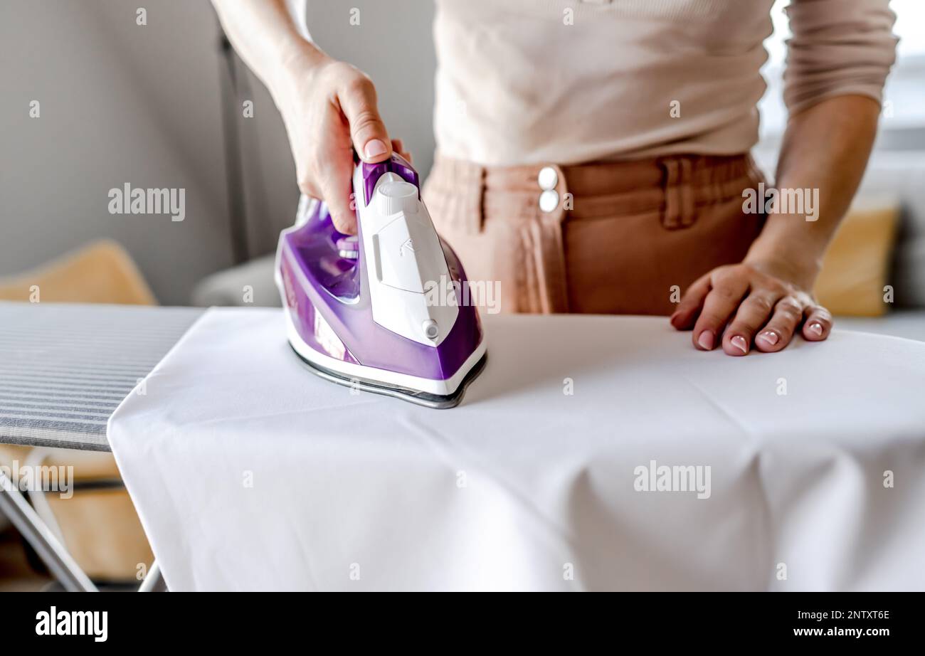 Girl hand using iron for wrinkled clothes Stock Photo - Alamy
