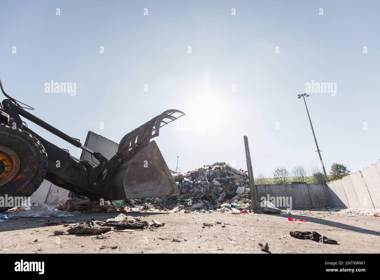 Yellow wheel loader, with lifted scrap grapple, moving along the ...