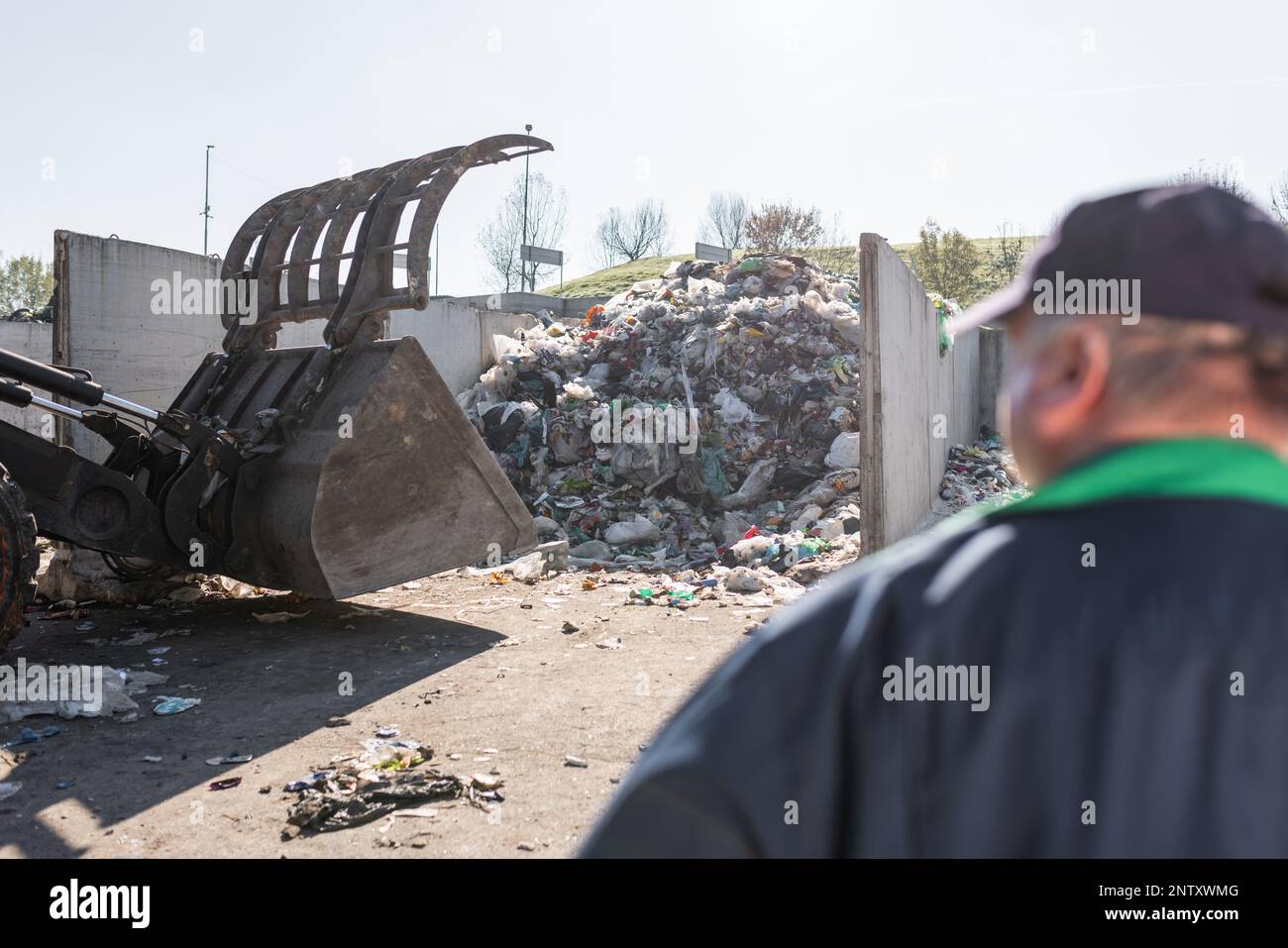 Recycling center worker, in dark blue work clothes, looking at an ...