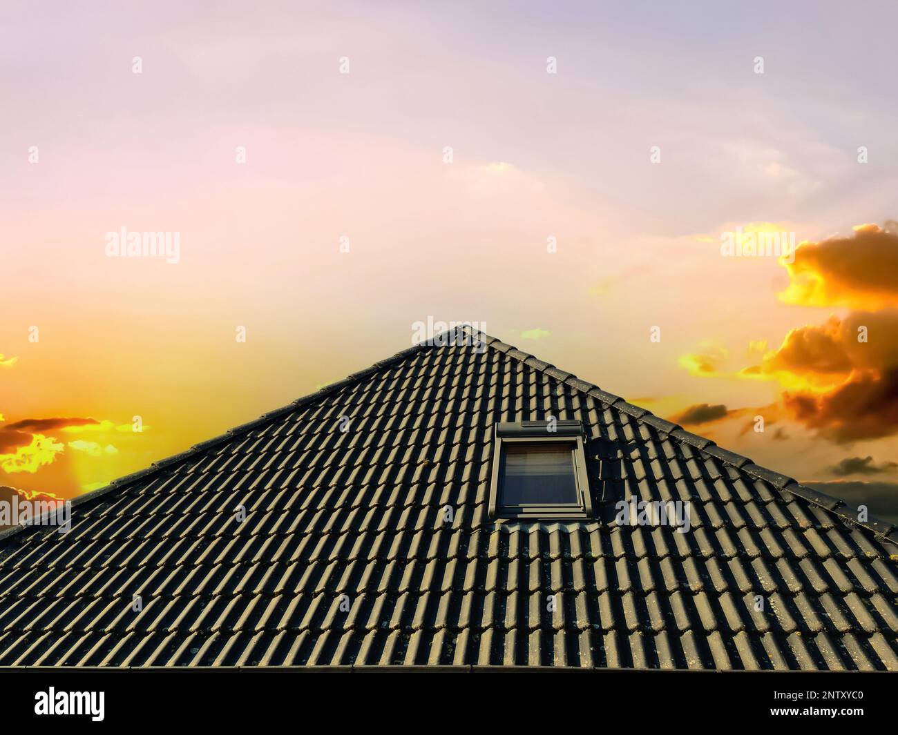 Colorful sunset. Open roof window in velux style with black roof tiles ...