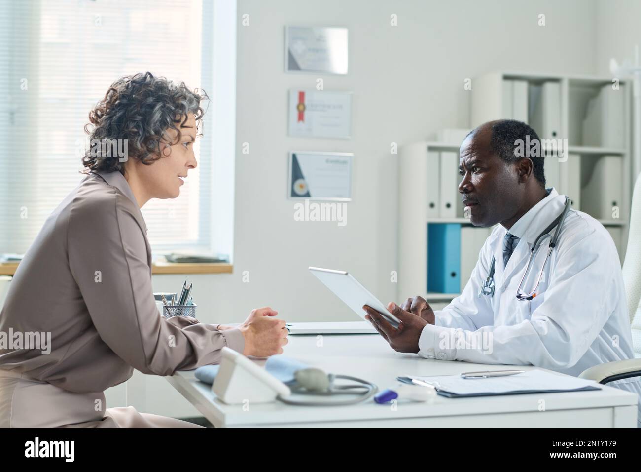Side view of experienced doctor with tablet filling in electronic ...