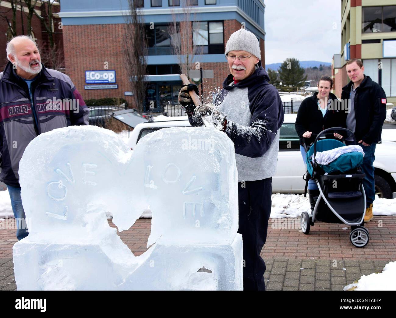 People watch as Peter Vacchina creates an ice sculpture, with a ...