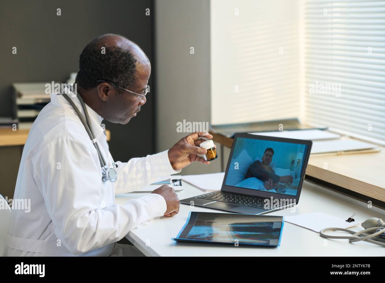 Mature African American general practitioner recommending pills to ...