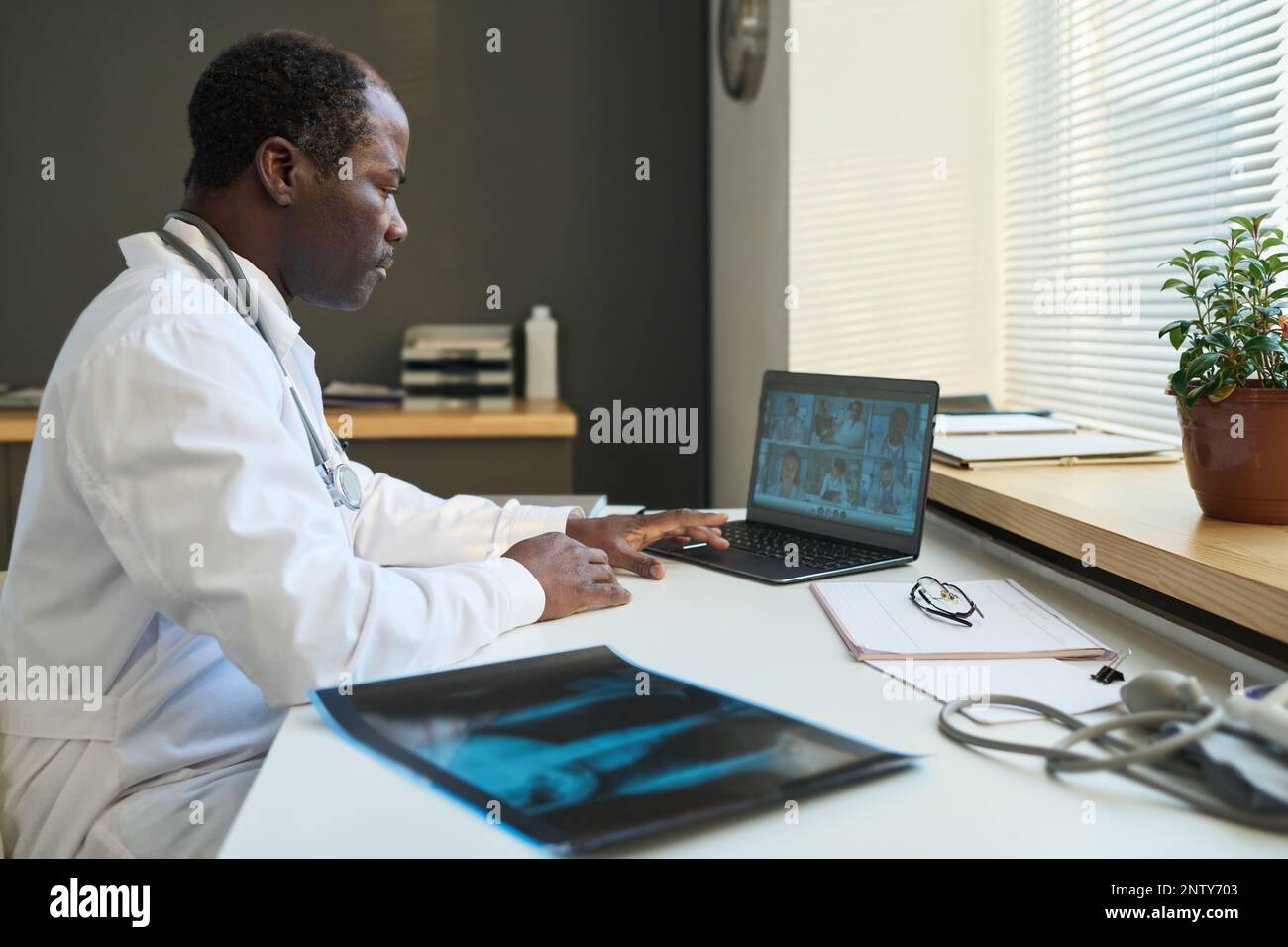 Serious mature African American male radiologist sitting by workplace ...
