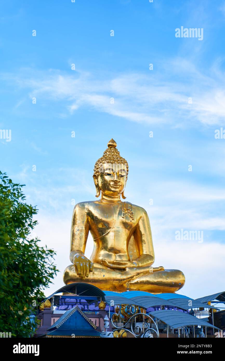 magnificent golden Buddha statue set against a clear blue sky. The ...