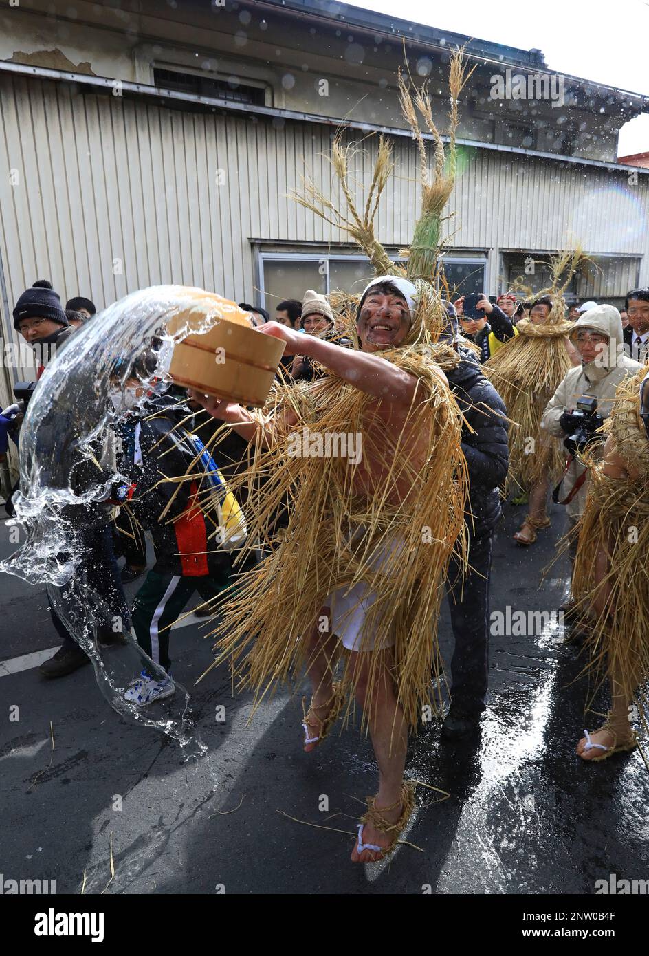 Straw-costumed men with soot-blackened faces scream and splash water ...