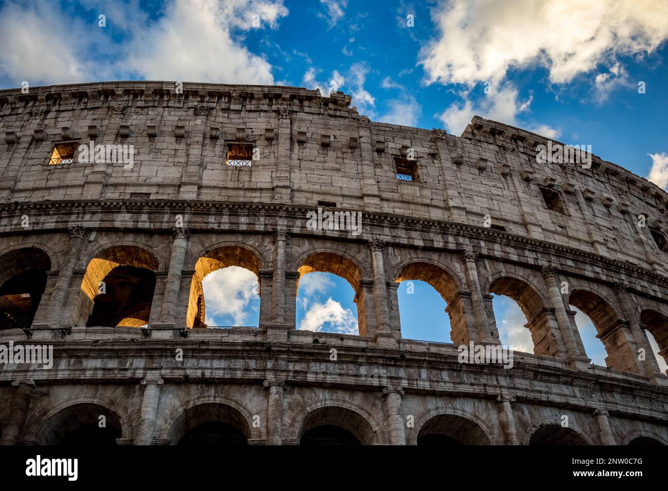 Low angle street view of the colosseum lit sideways. Rome, the capital ...