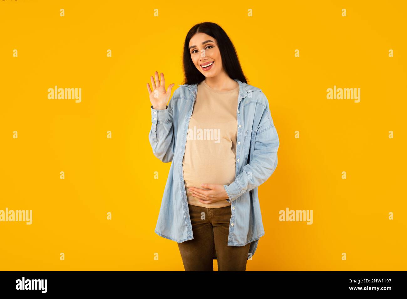 Beautiful Expectant Woman Touching Pregnant Belly And Waving Saying Hello And Smiling At Camera