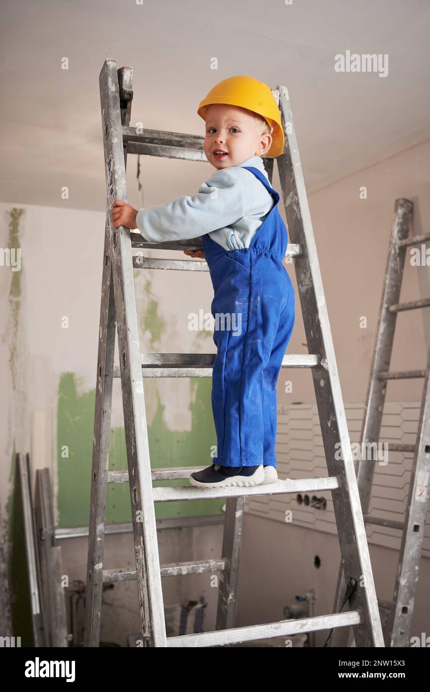 Child construction worker on the top of ladder while working on home ...