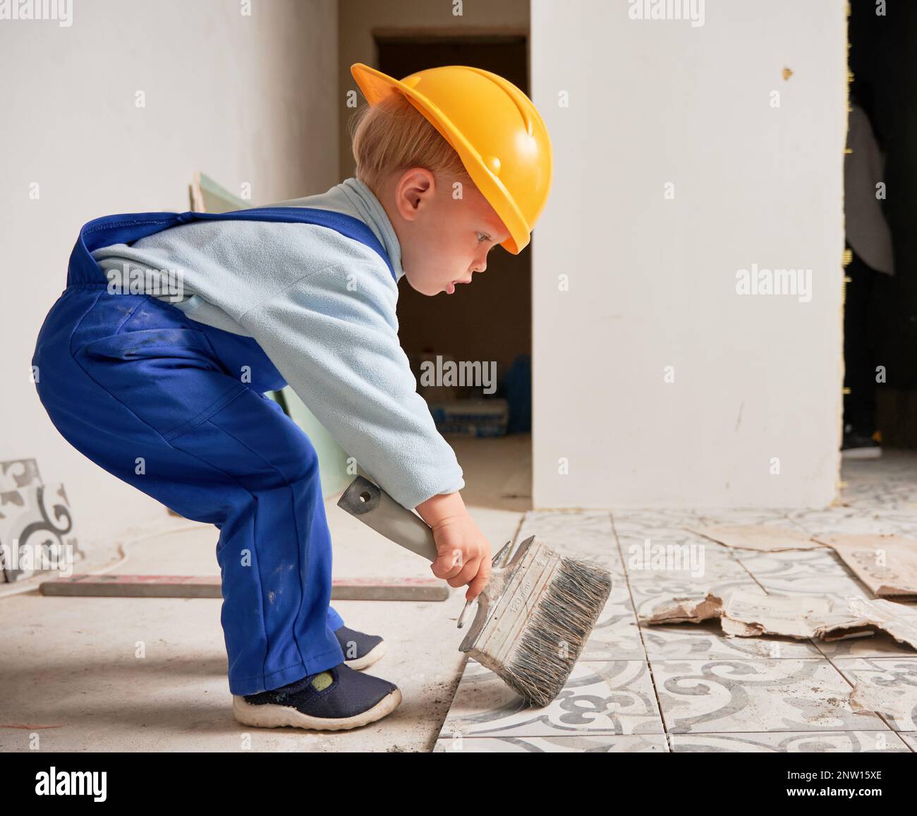 Side view of little boy construction worker using brush while playing ...