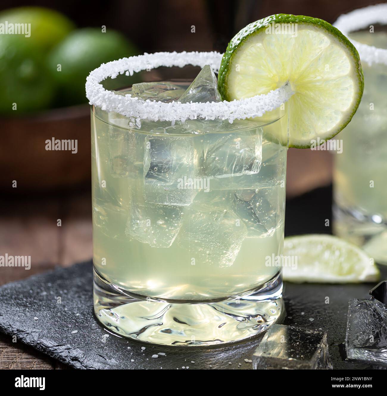 Margarita cocktail with ice, lime slice and salt rim on a black slate ...