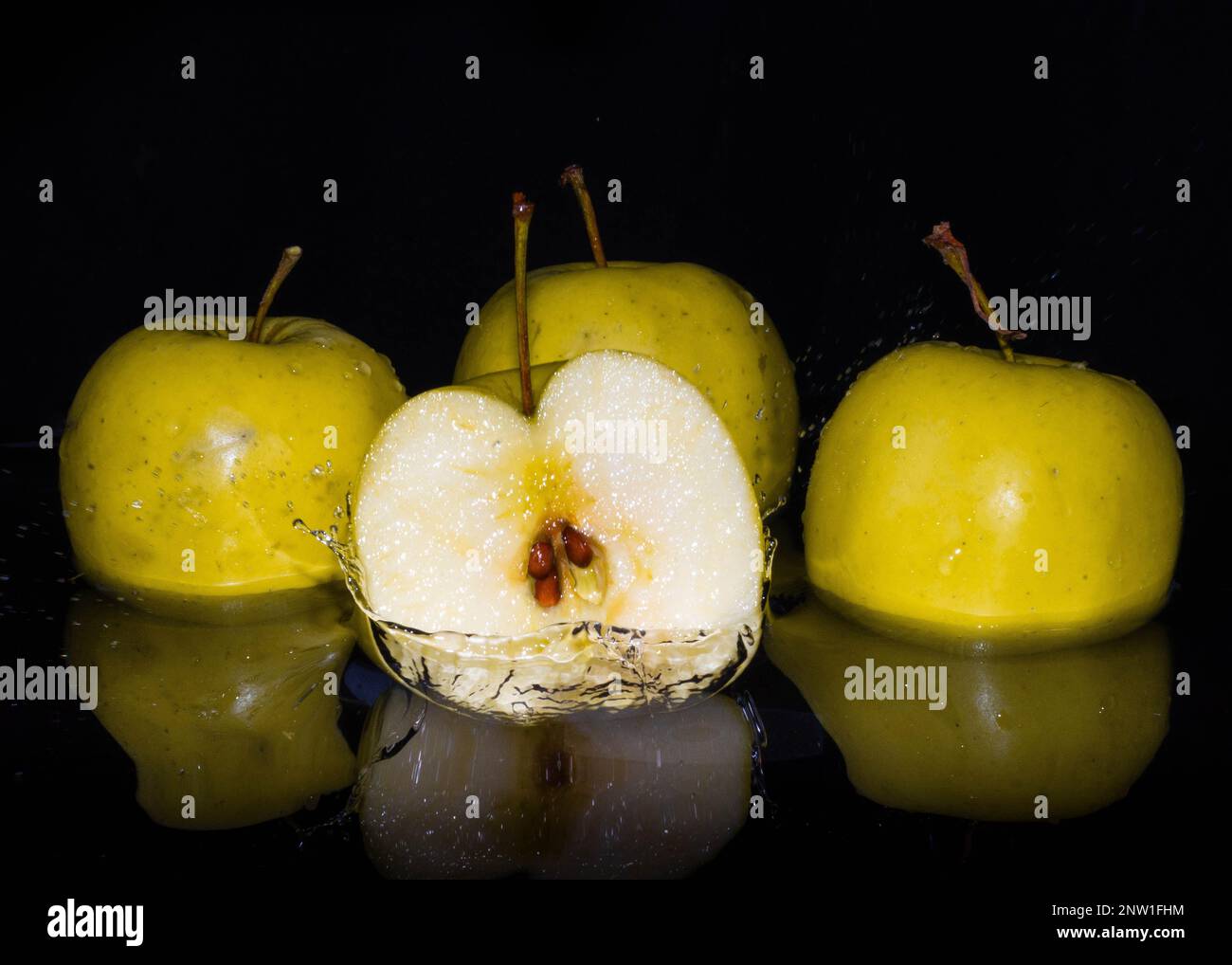The freshly sliced yellow apples on a water surface with a splash of ...