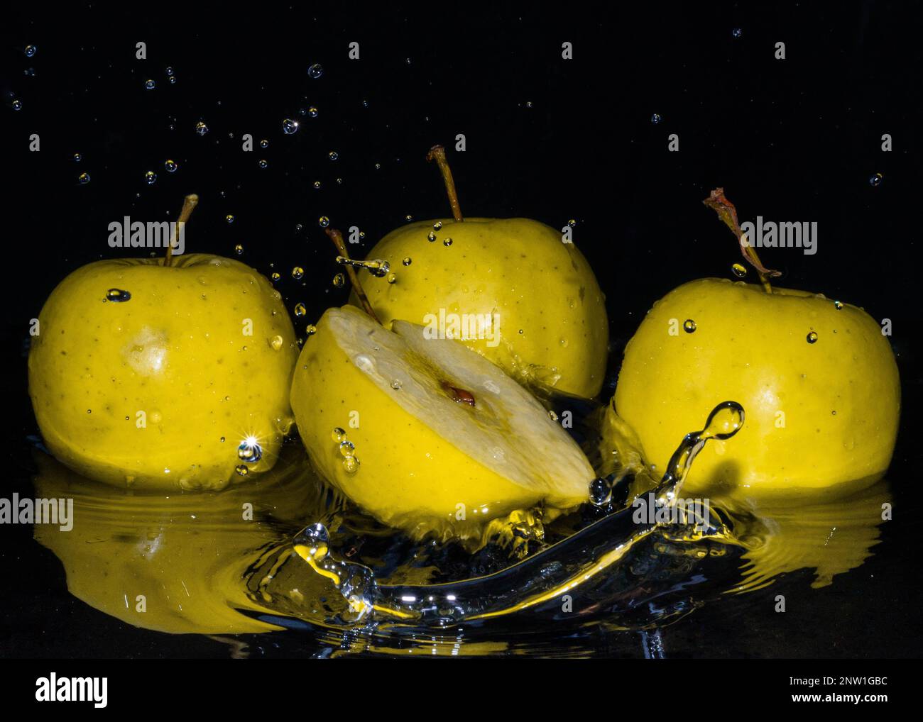 The freshly sliced yellow apples on a water surface with a splash of ...