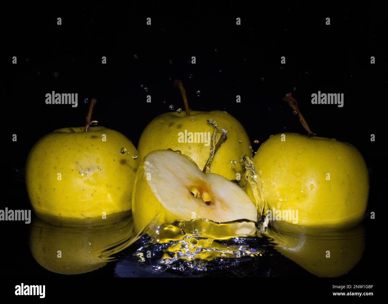 The freshly sliced yellow apples on a water surface with a splash of ...