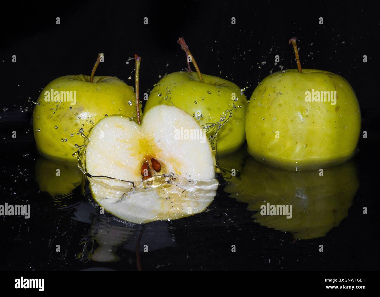The freshly sliced yellow apples on a water surface with a splash of ...