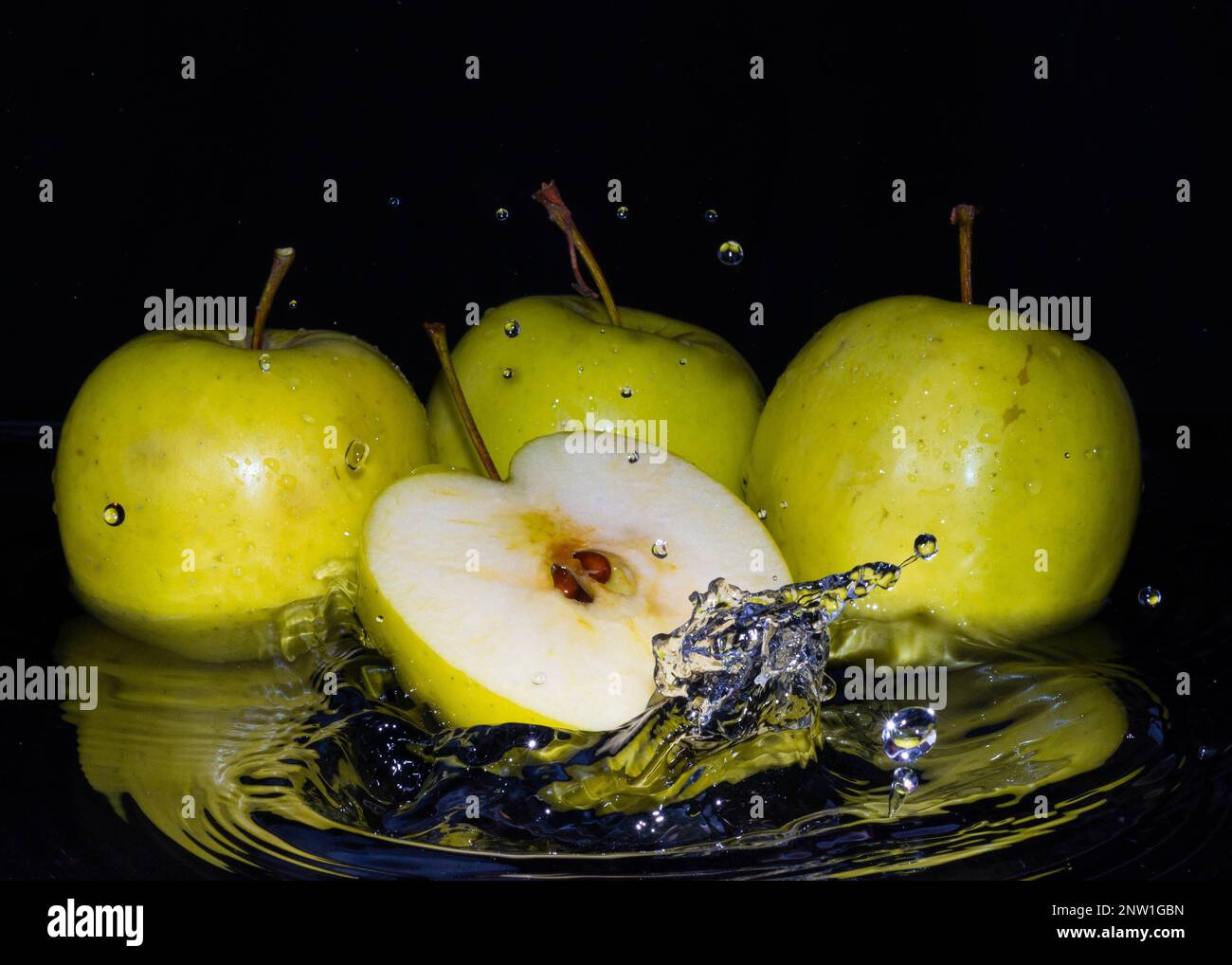 The freshly sliced yellow apples on a water surface with a splash of ...