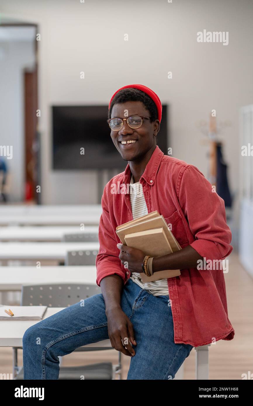 Happy smiling African guy university student in classroom or library ...