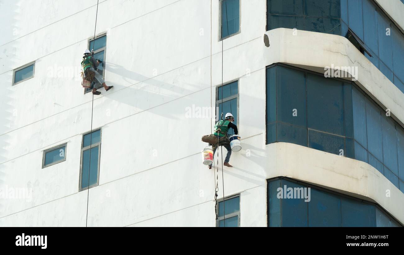 Industrial climbers paint high-rise walls and wash windows Stock Photo ...