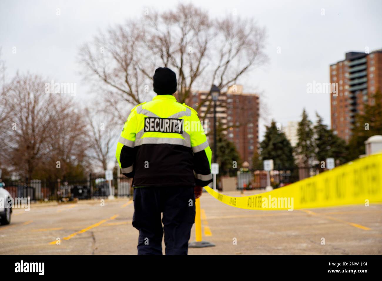 Security guard setting up a caution tape to do parking enforcement at ...