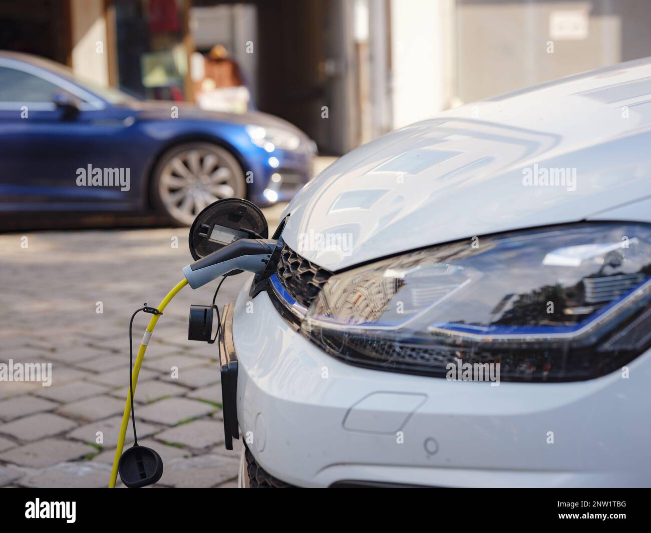 Electric car with opened charging socket cap and charger plugged in, at ...