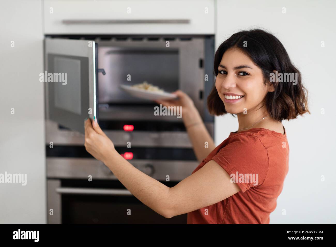 Portrait Of Happy Young Arab Woman Using Microwave In Modern Kitchen ...