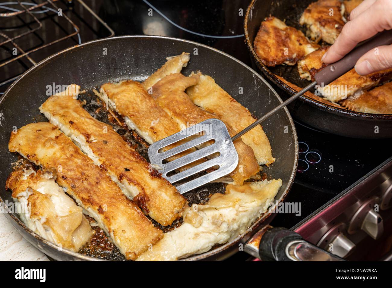 the cook checks the readiness of the fish with a fork Stock Photo - Alamy