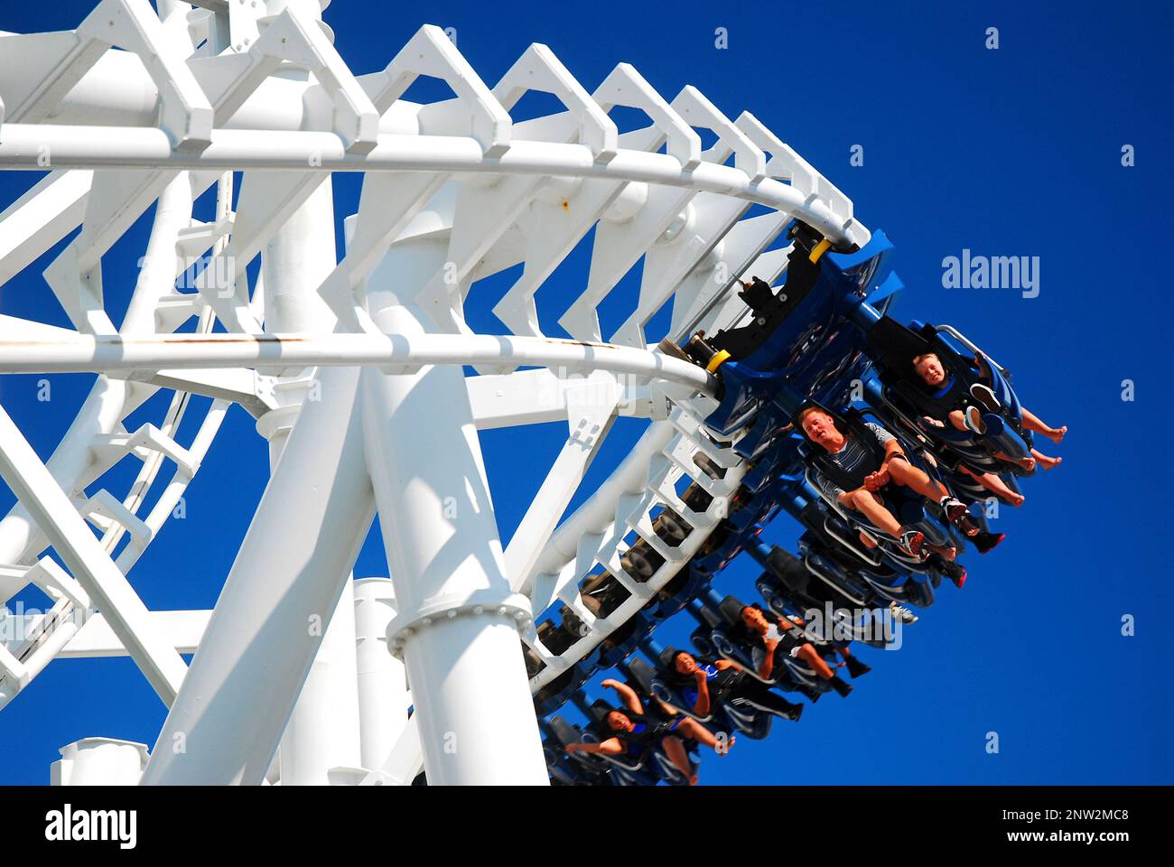 Thrill seeks zoom around a curve on a roller coaster on a sunny summer ...