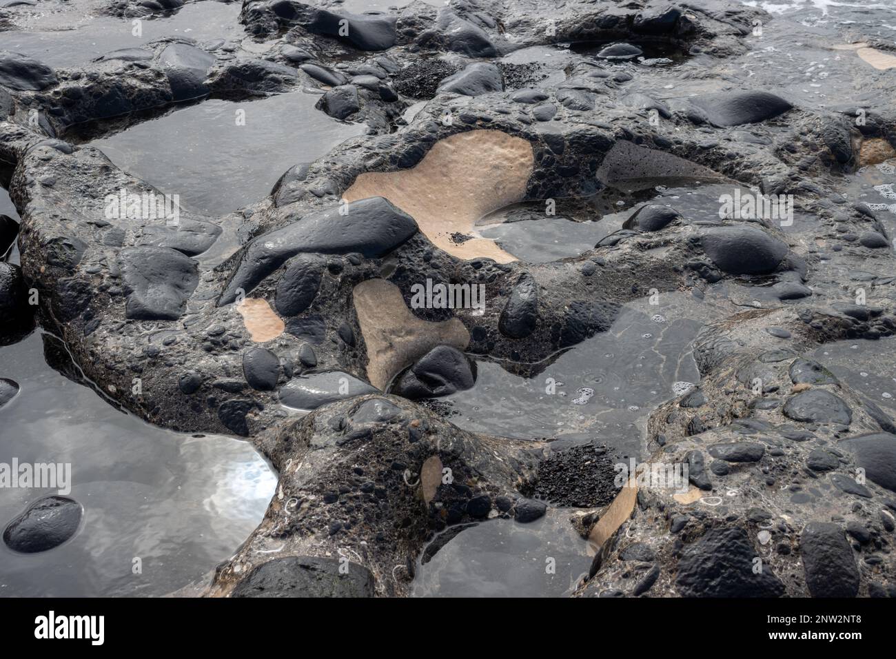 Round shapes of a rock on the Atlantic ocean coast. Black or dark grey ...