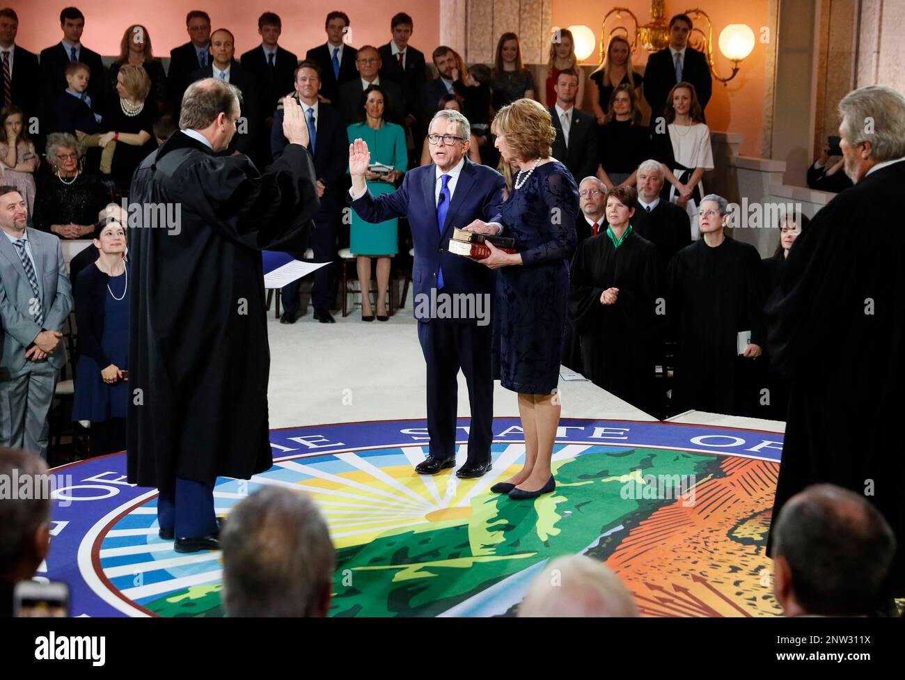 Ohio Governor Mike DeWine, center, takes the oath of office alongside ...