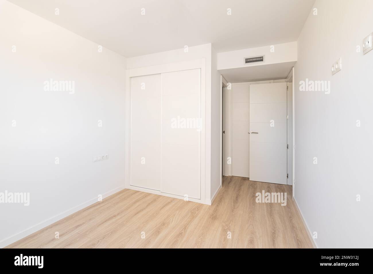 White empty sunny room with built-in wardrobe ventilation and two doors ...
