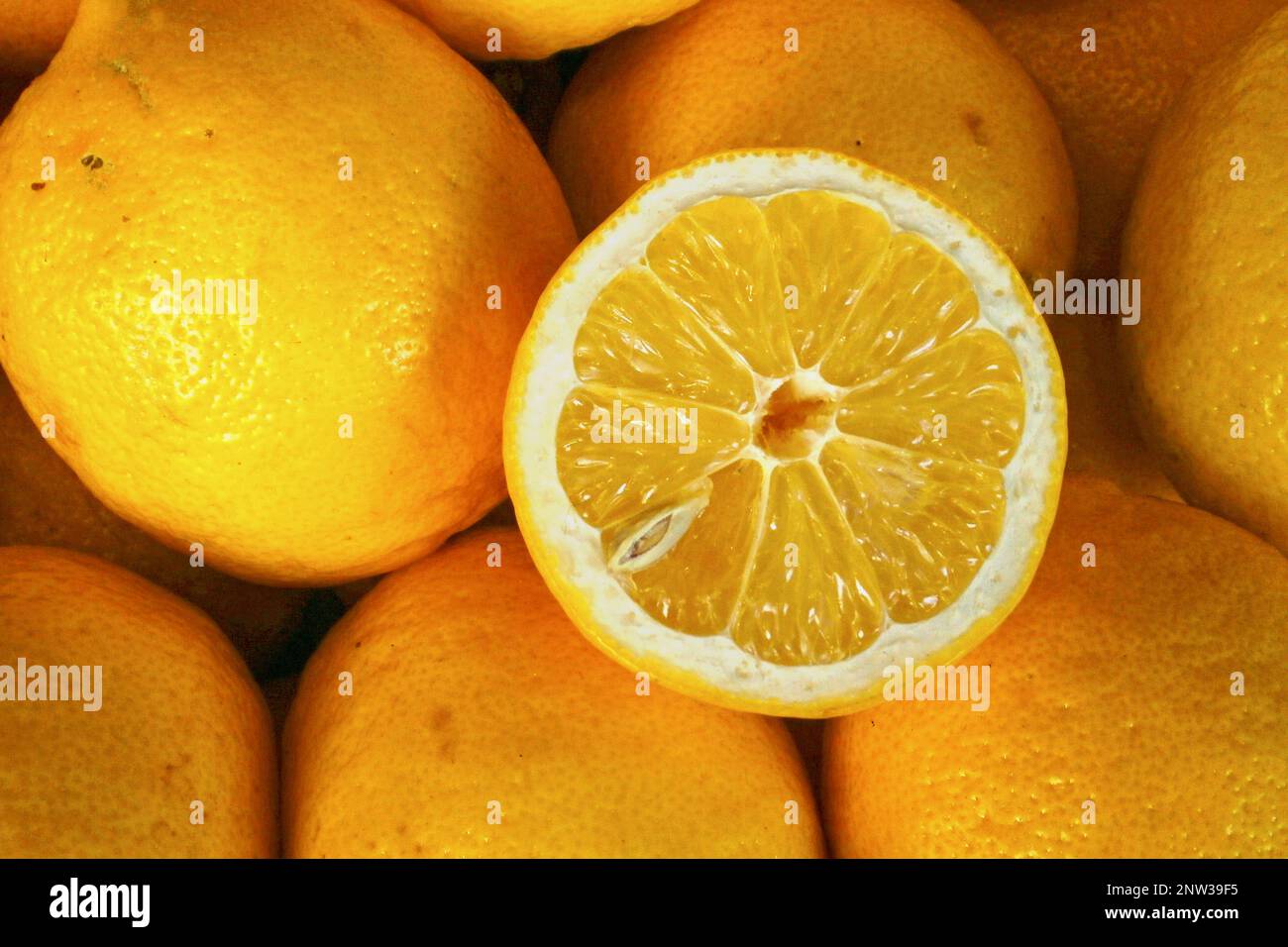 Full frame close-up on a stack of lemons with one cut in half on a ...