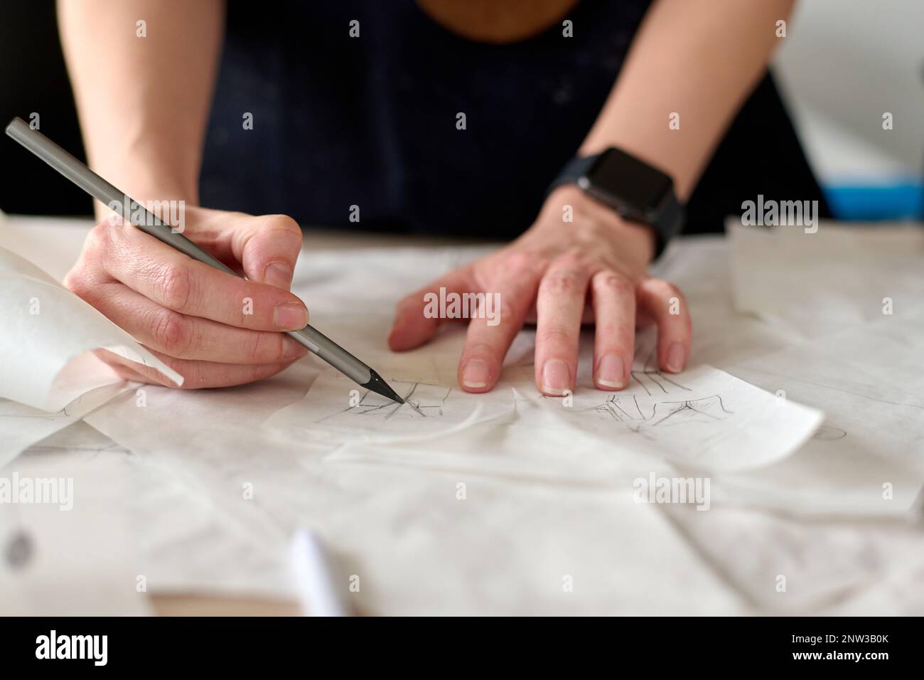 Hands of creative female tailor with pencil drawing sketches of new ...