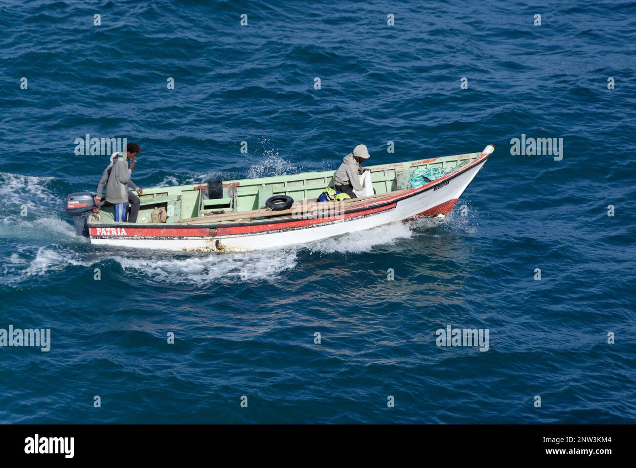 Two fishermen in a small boat heading out to their fishing grounds off ...