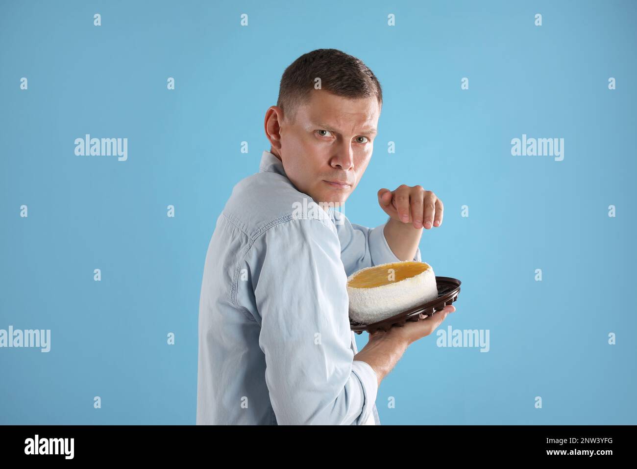 Greedy man hiding tasty cake on turquoise background Stock Photo - Alamy