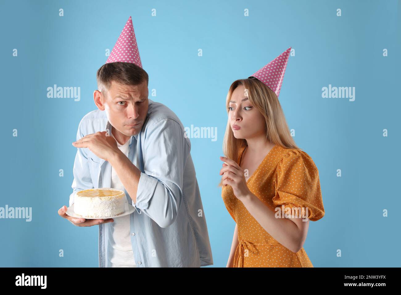 Greedy man hiding birthday cake from woman on turquoise background ...