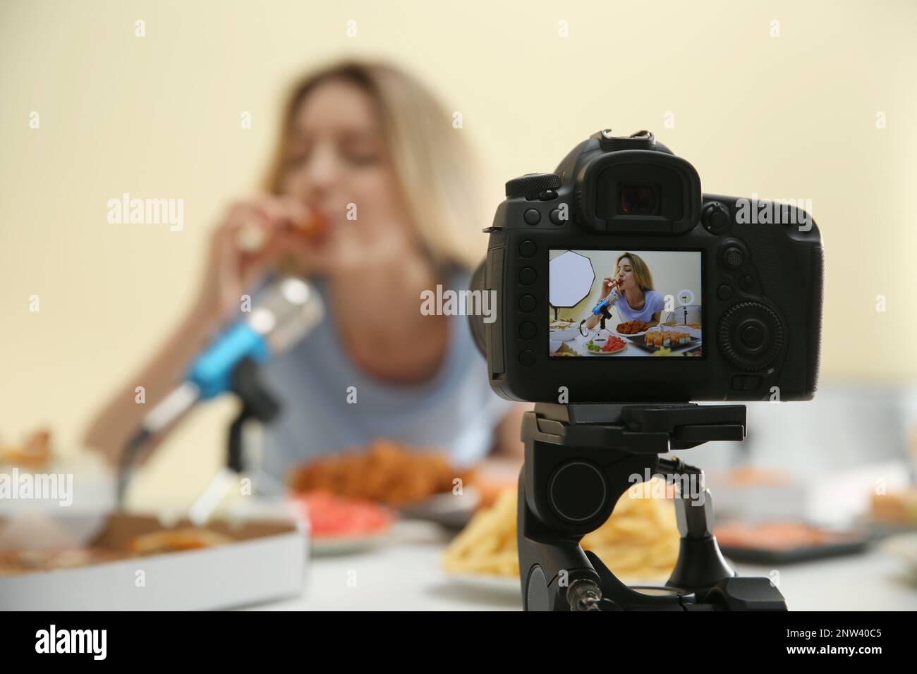 Food blogger recording eating show against light background, focus on ...