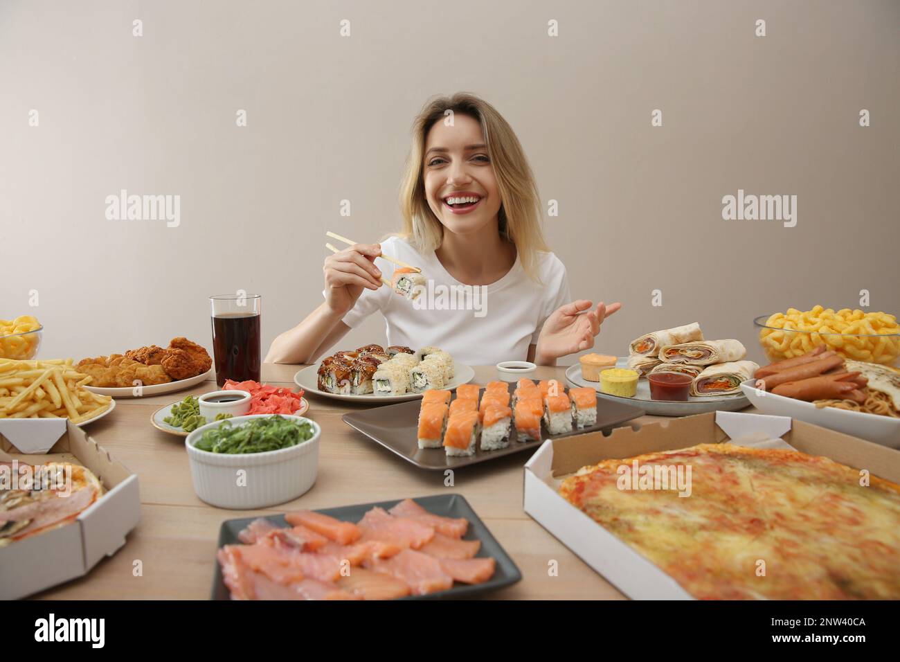Food blogger eating at table against beige background. Mukbang vlog ...