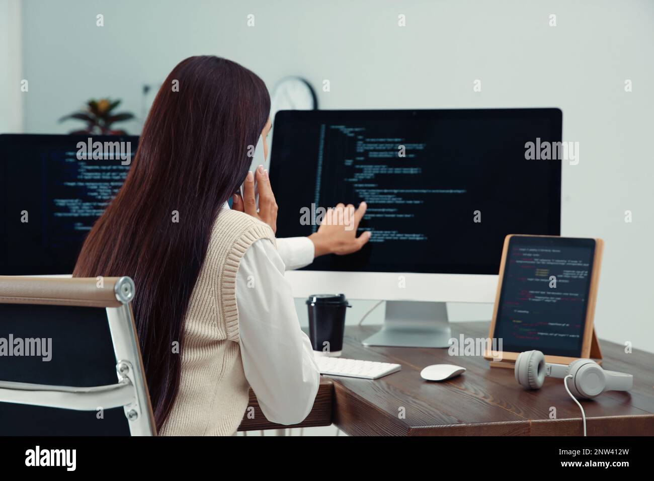 Programmer talking on phone while working at desk in office Stock Photo - Alamy