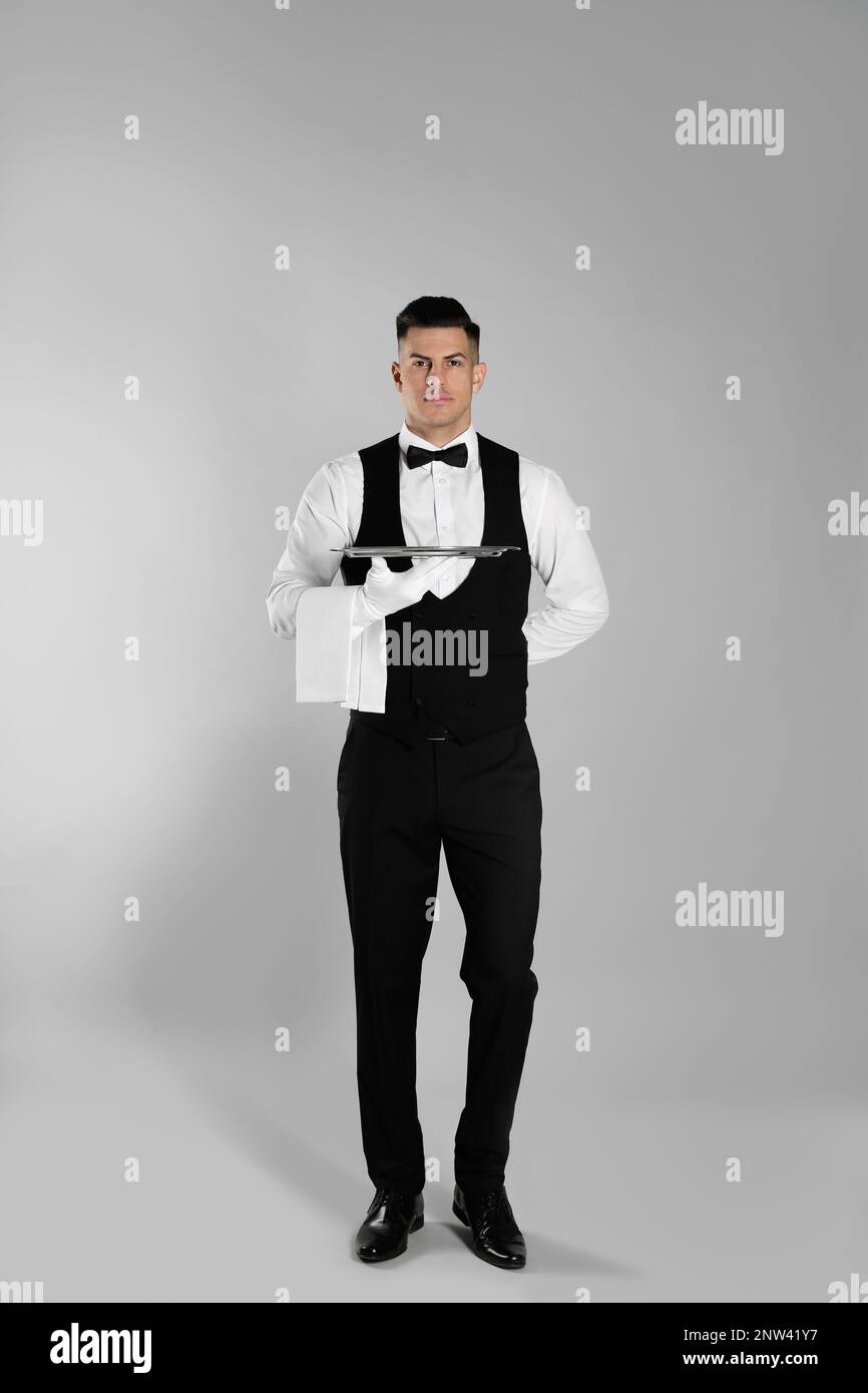 Handsome butler with tray on light grey background Stock Photo - Alamy