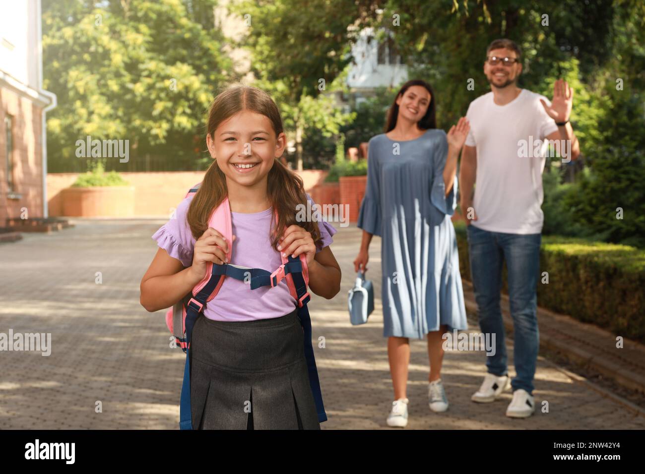 Parents waving goodbye to their daughter before school outdoors Stock ...