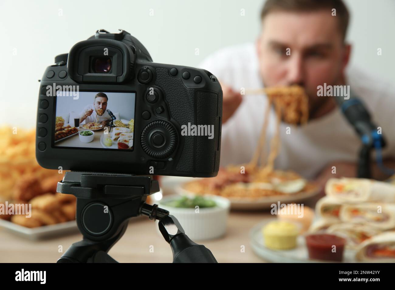 Food blogger recording eating show against light background, focus on ...
