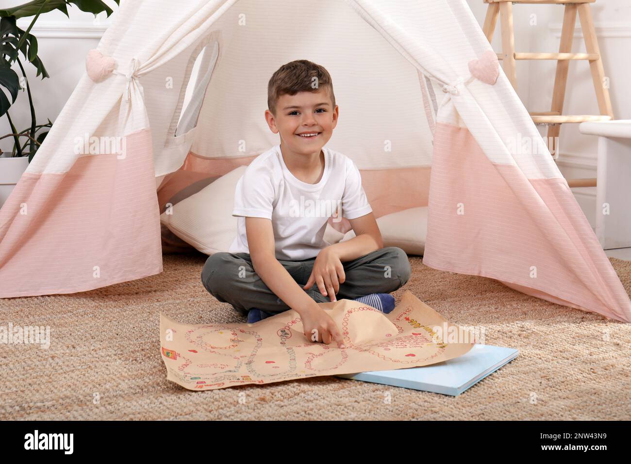 Cute little boy with treasure map near toy wigwam at home Stock Photo ...